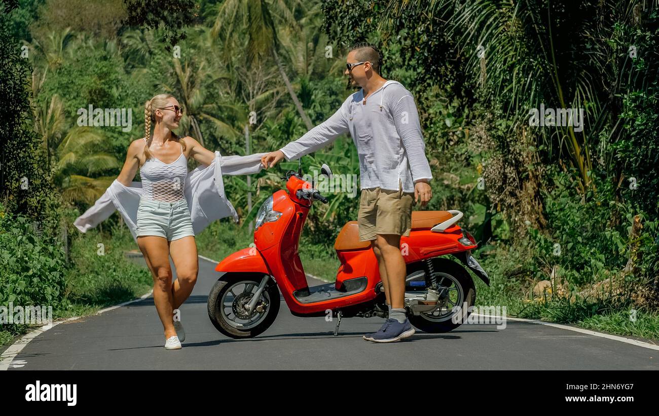 Two caucasian tourist woman man dance near scooter. Love couple on red ...