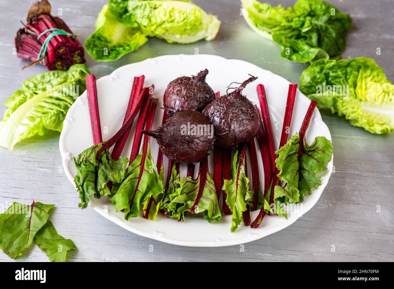 Baked beetroot on white plate, green lettuce leaf on silver background ...