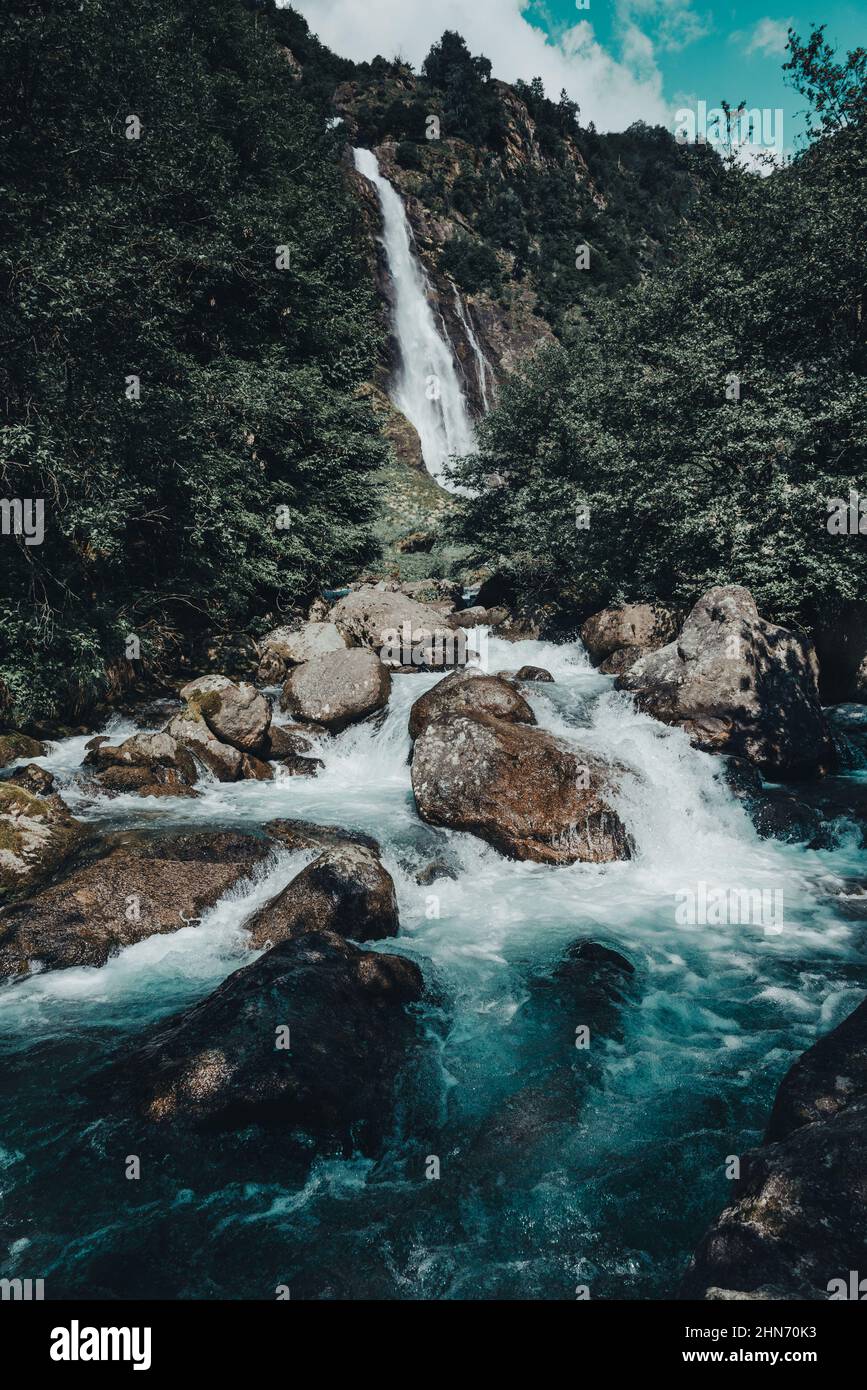 Vertical shot of the beautiful waterfall over the hill with dense ...