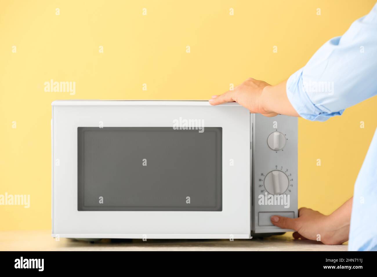 Woman opening microwave oven on color background, closeup Stock Photo ...