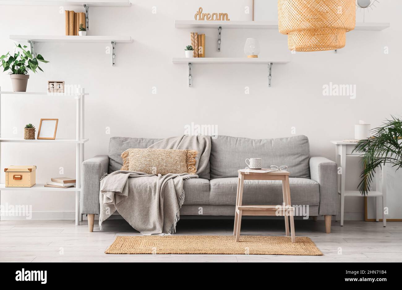 Interior of light living room with comfortable sofa, shelves and wicker ...