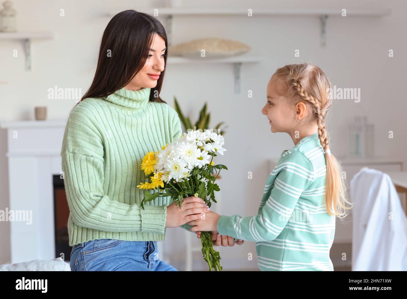Little girl greeting her mother with flowers at home Stock Photo - Alamy