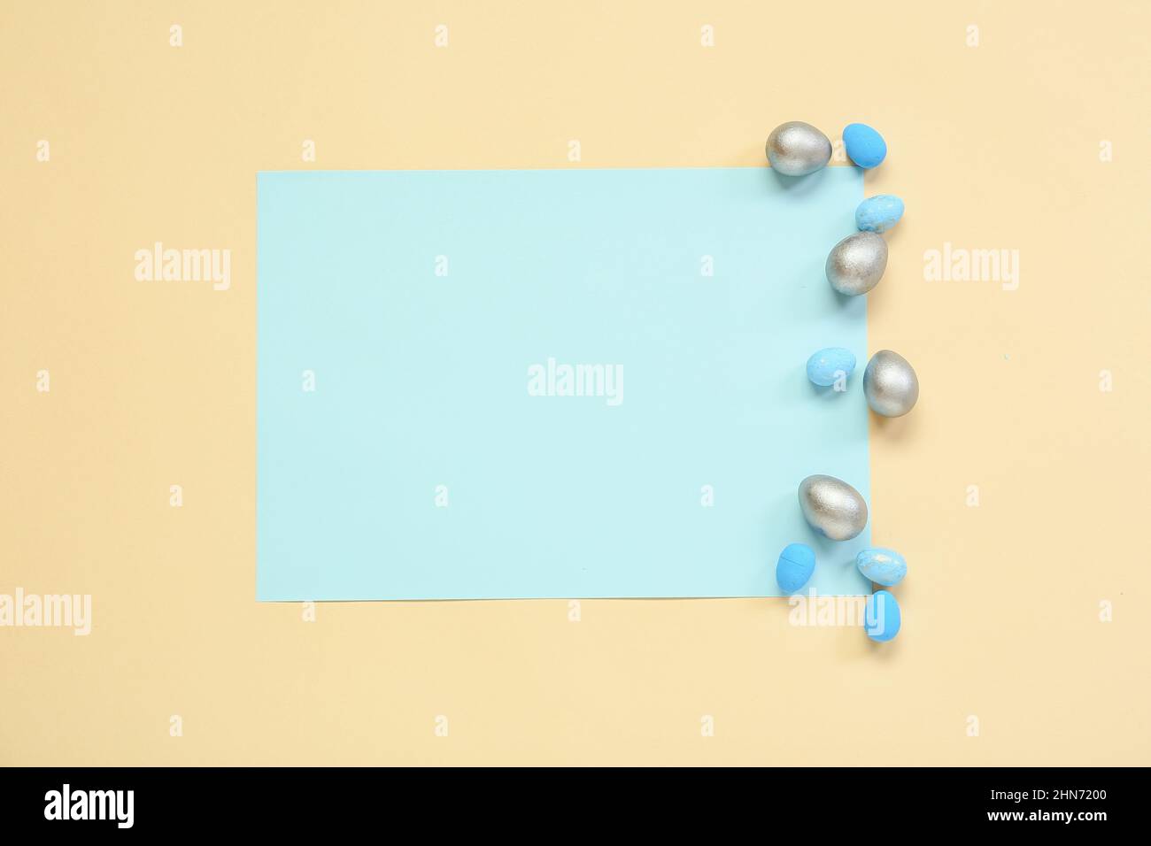 Composition with sheet of paper and Easter eggs on blue background ...