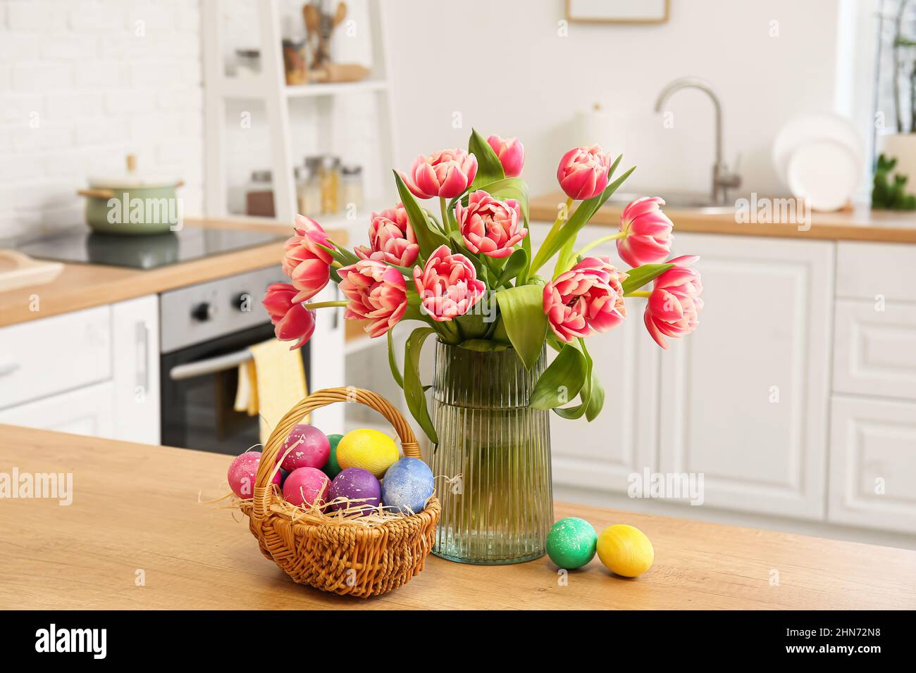 Basket of Easter eggs and vase with tulips on kitchen counter Stock ...