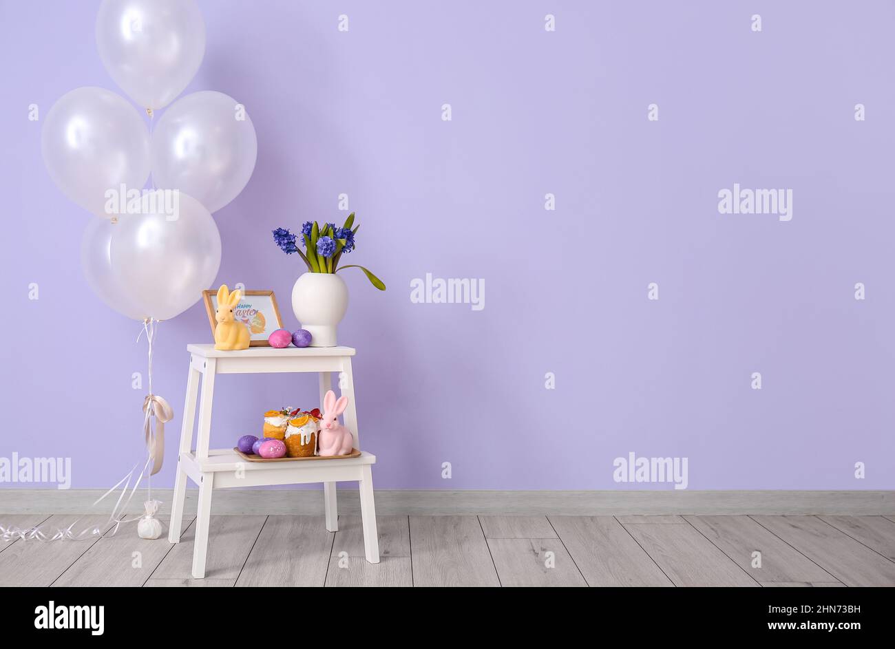 Easter cakes, eggs, vase with flowers and stylish decor on stepladder ...