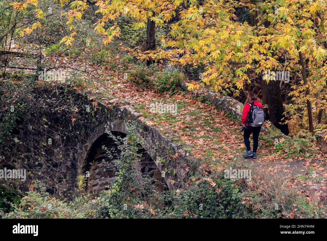 Landscape photographer walking on a hiking trail above an ancient stone ...