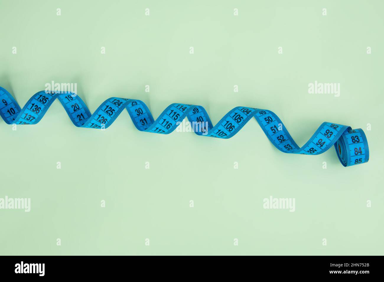 Blue tape measure on the bright light grenn background Stock Photo - Alamy