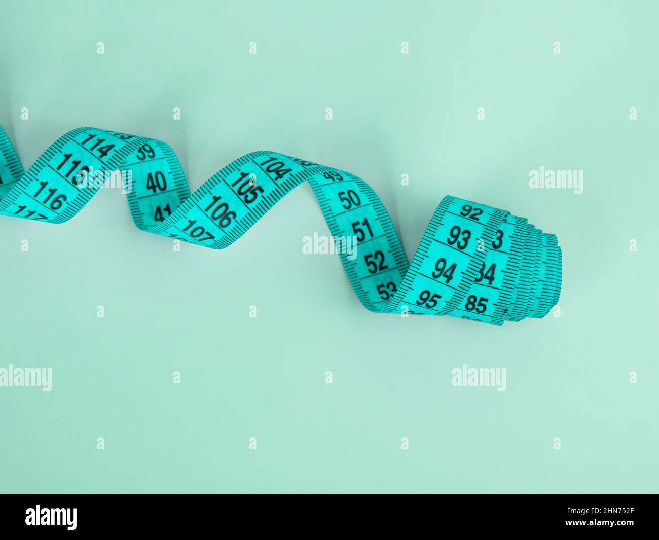 Green tape measure on the bright light green background Stock Photo - Alamy