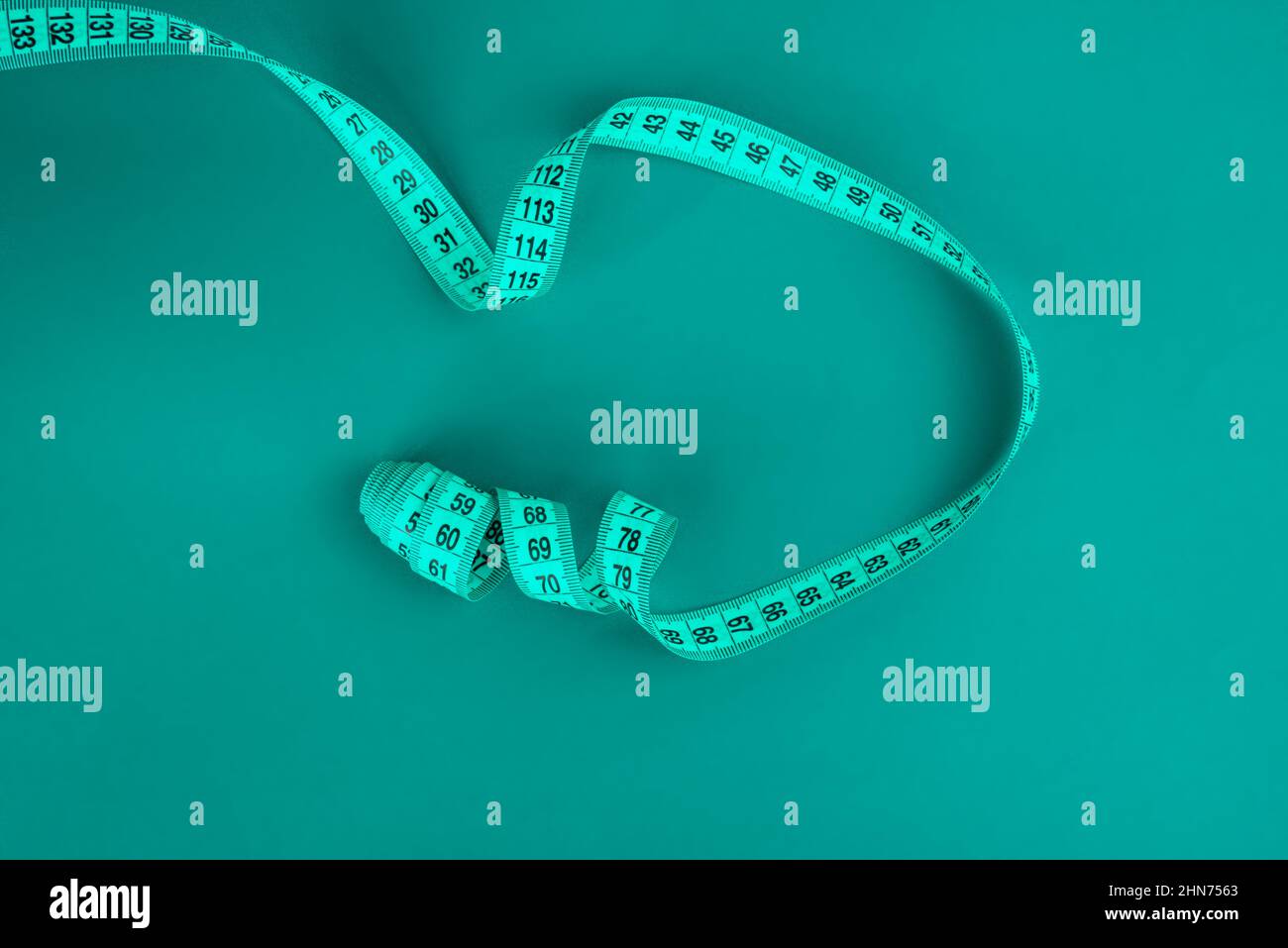 Green tape measure on the bright light green background Stock Photo - Alamy