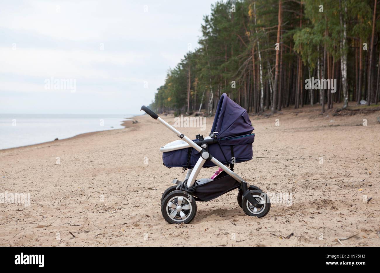 Modern baby stroller standing on empty sandy beach, side view, nobody ...