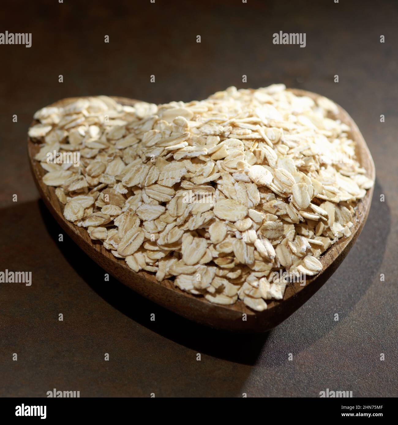 Heap of oat flakes in a shape of heart. Oatmeal heart on a dark ...