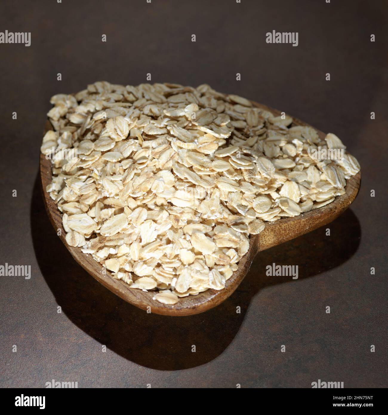 Heap of oat flakes in a shape of heart. Oatmeal heart on a dark ...