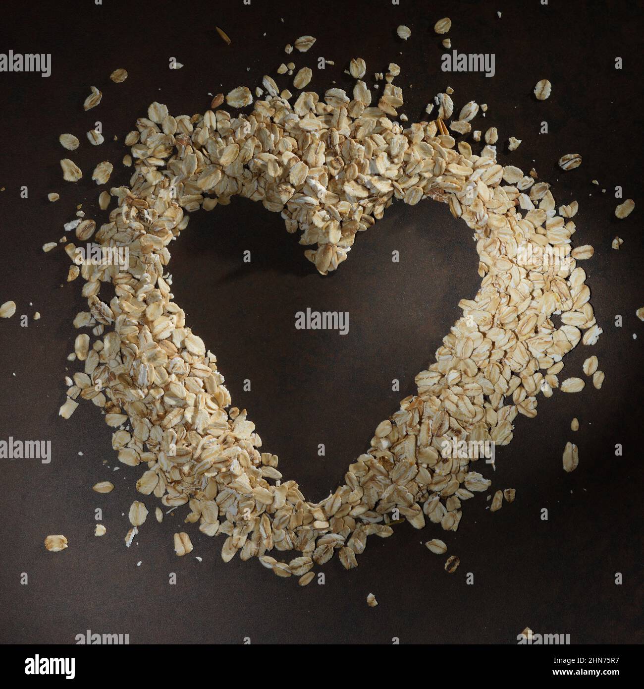 Heap of oat flakes in a shape of heart. Oatmeal heart on a dark ...
