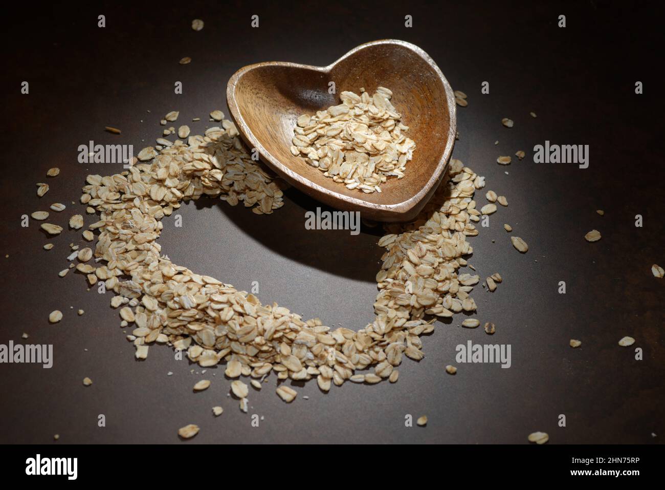 Heap of oat flakes in a shape of heart. Oatmeal heart on a dark ...