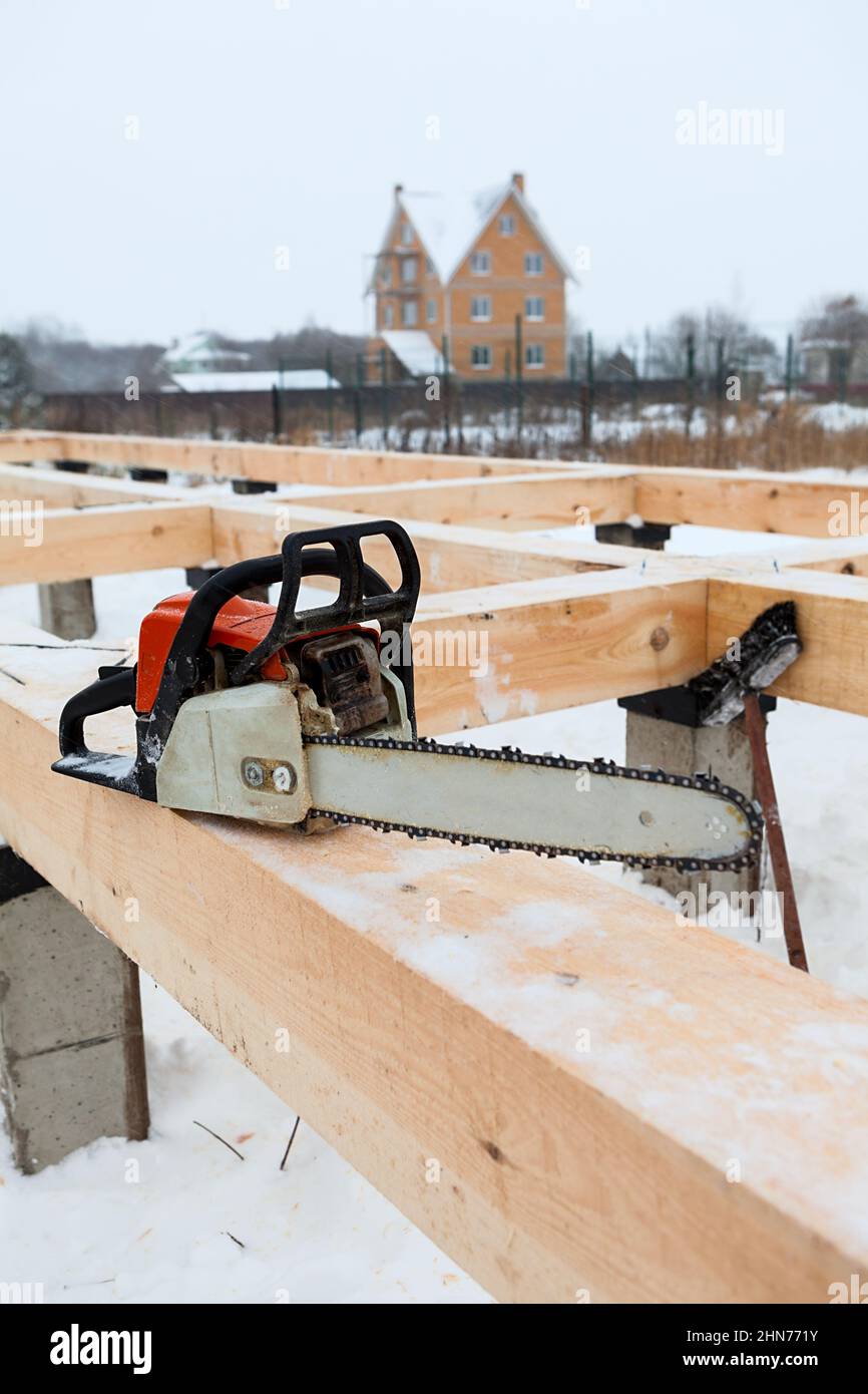 Chainsaw on a wooden strapping of a pile foundation of a frame house ...