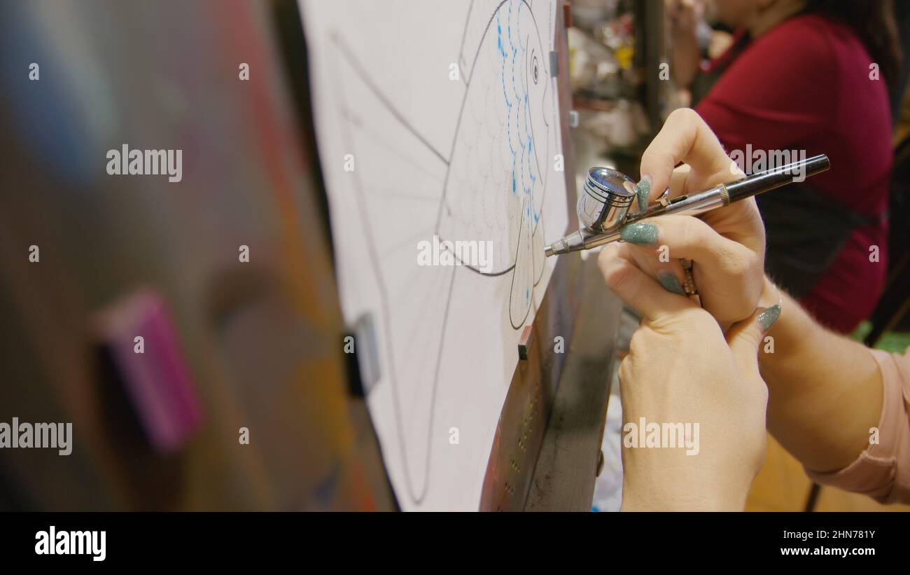 Woman artist learns to paint with airbrush with acrylic dye, paper and ...