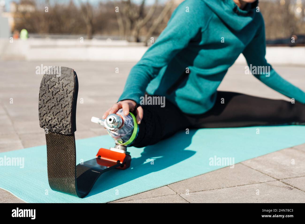 Young sportswoman with prosthesis doing exercise while working out on ...