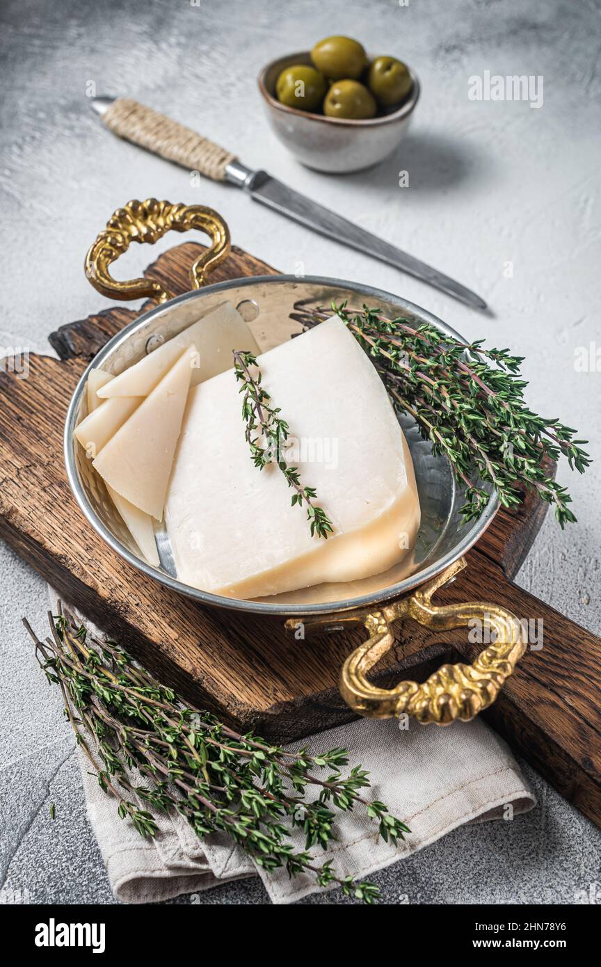French hard goat cheese in a skillet with herbs. White background. Top ...