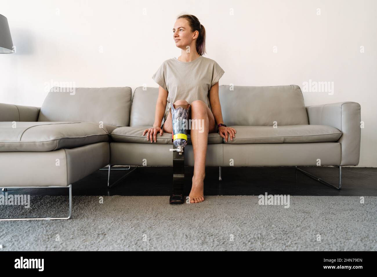 Smiling young white disabled woman with prostetic leg sitting on a ...