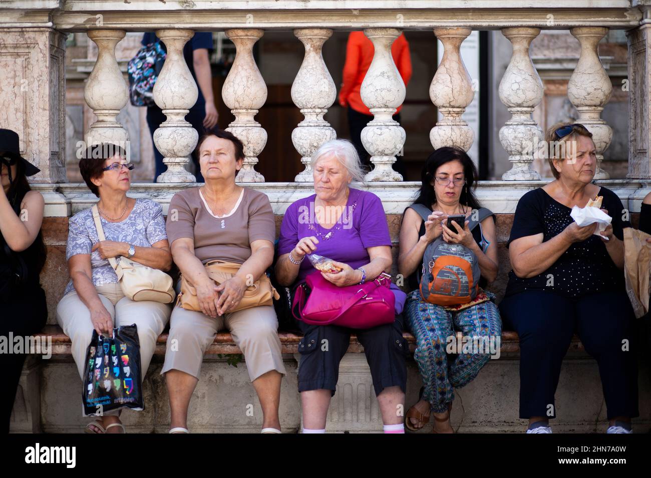 tourists taking a break on a seating area in st marks square during the ...