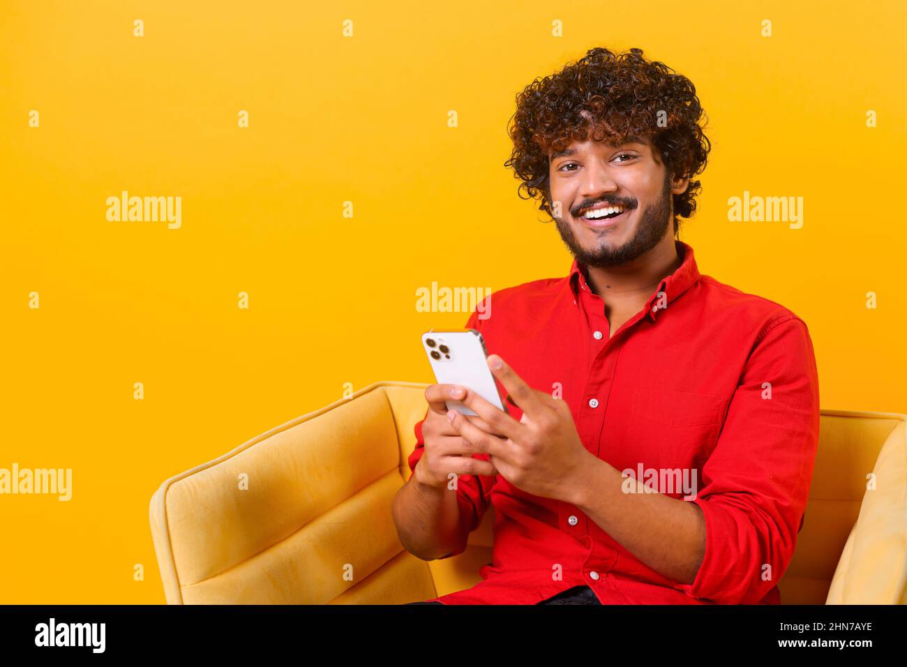 Happy Indian man looking at the camera, scrolling and typing message or ...