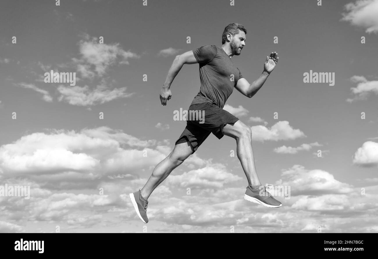 sportsman with muscular body running in sportswear outdoor on sky ...