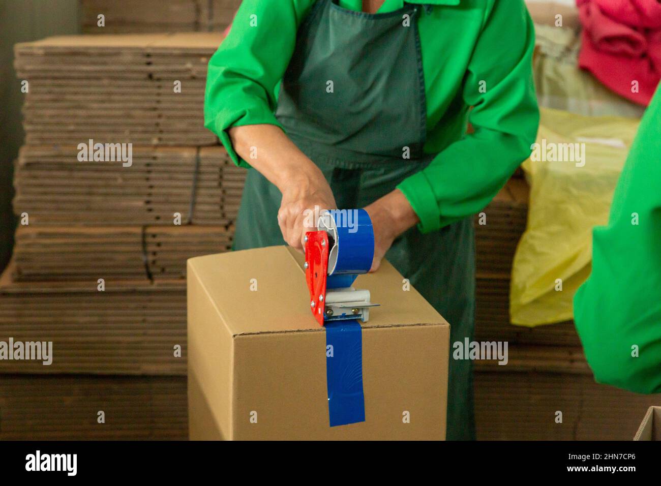 Woman in warehouse worker uniform packing cardboard box to delivery ...