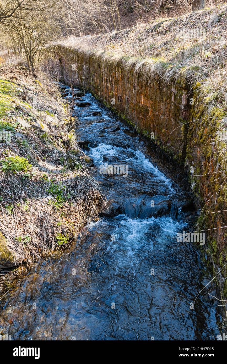 Long mountain stream next to mountain trail with high wall next to ...