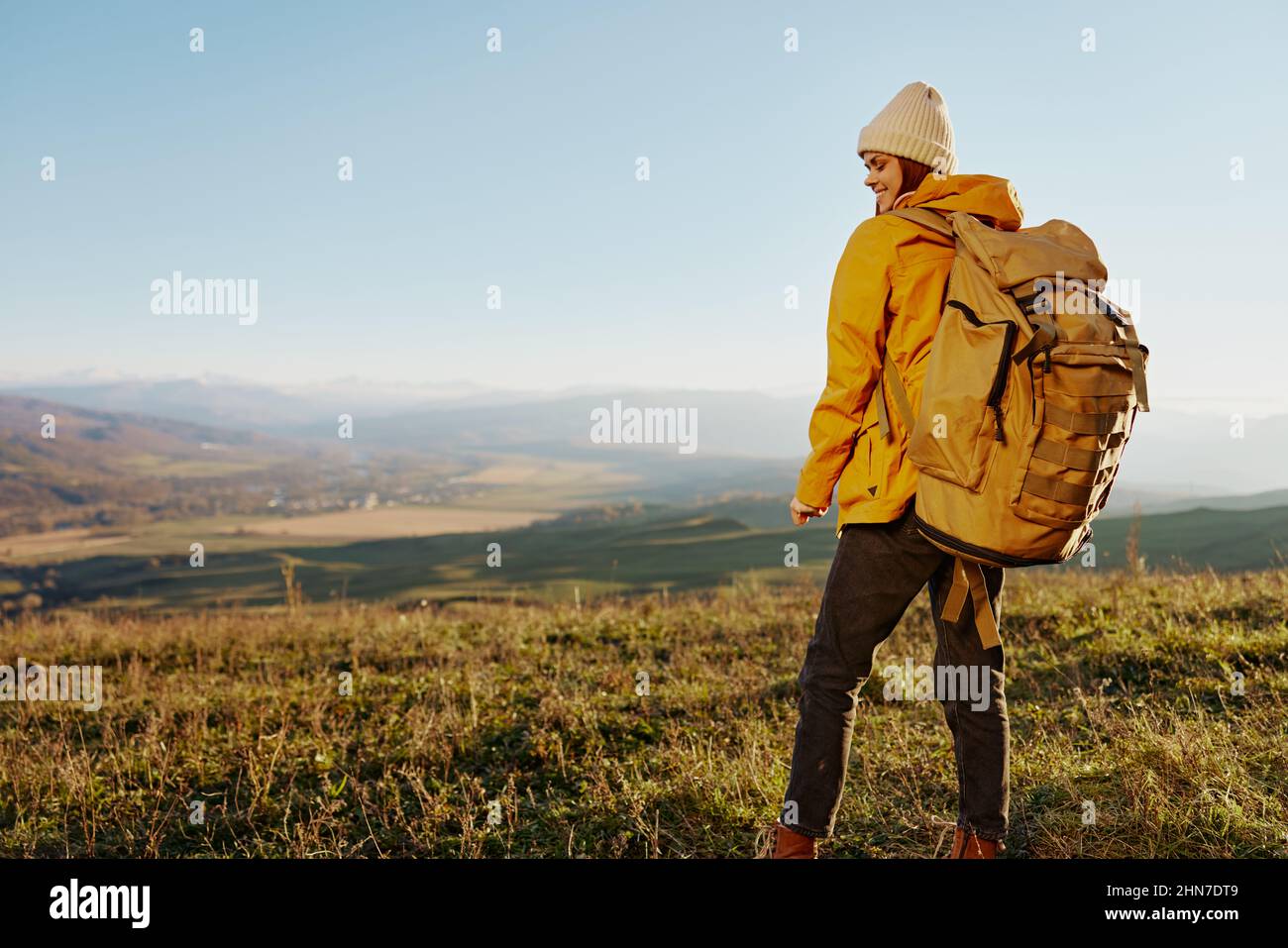 woman traveler in a yellow jacket in a hat backpack travel mountains ...