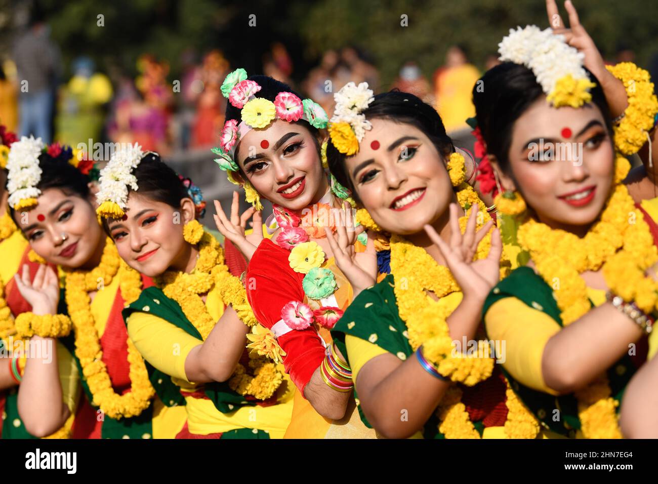 Women wearing traditional saris and floral ornaments pose for picture ...