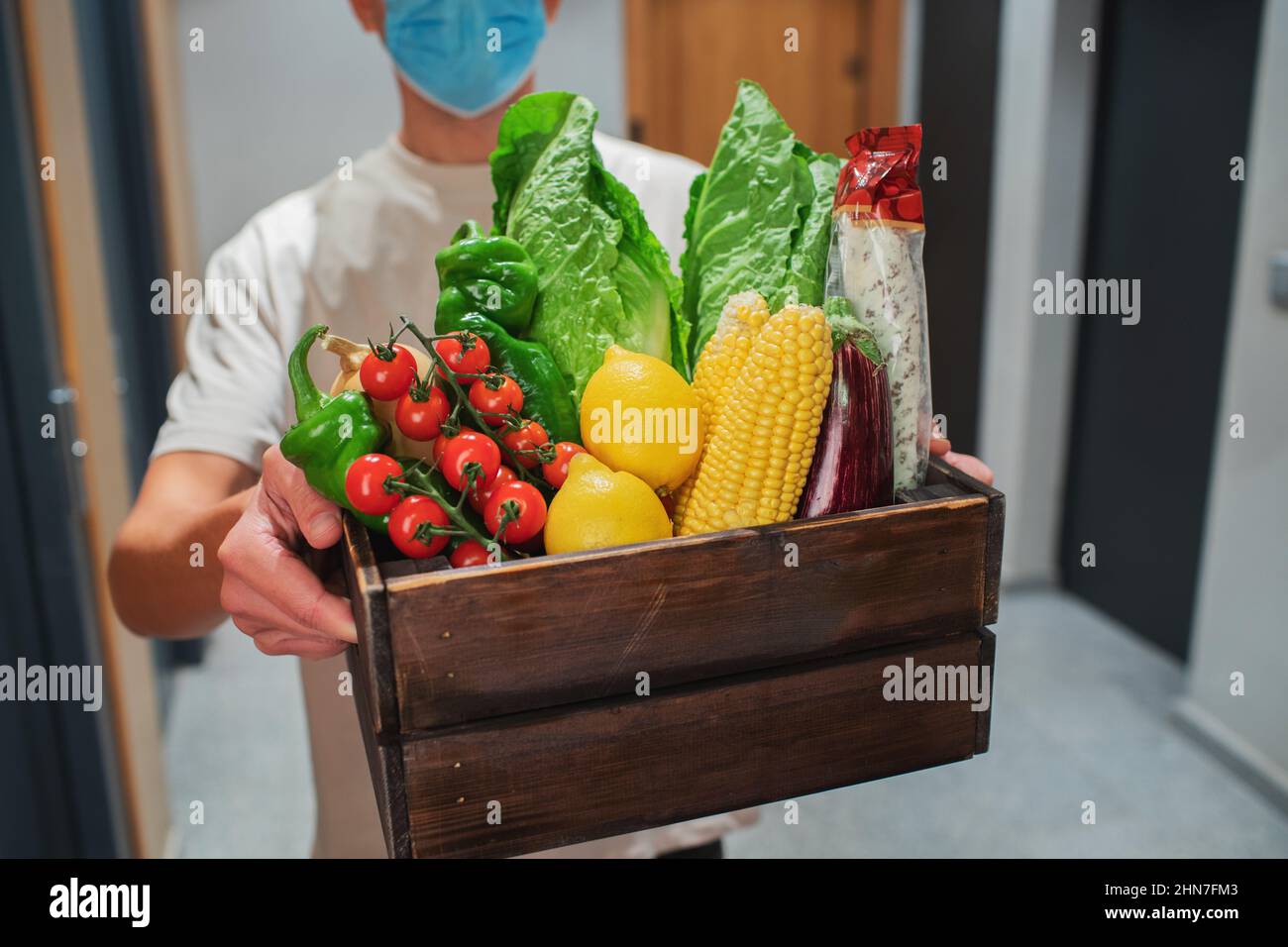 Delivery man in protective mask holding paper bag with food in the ...