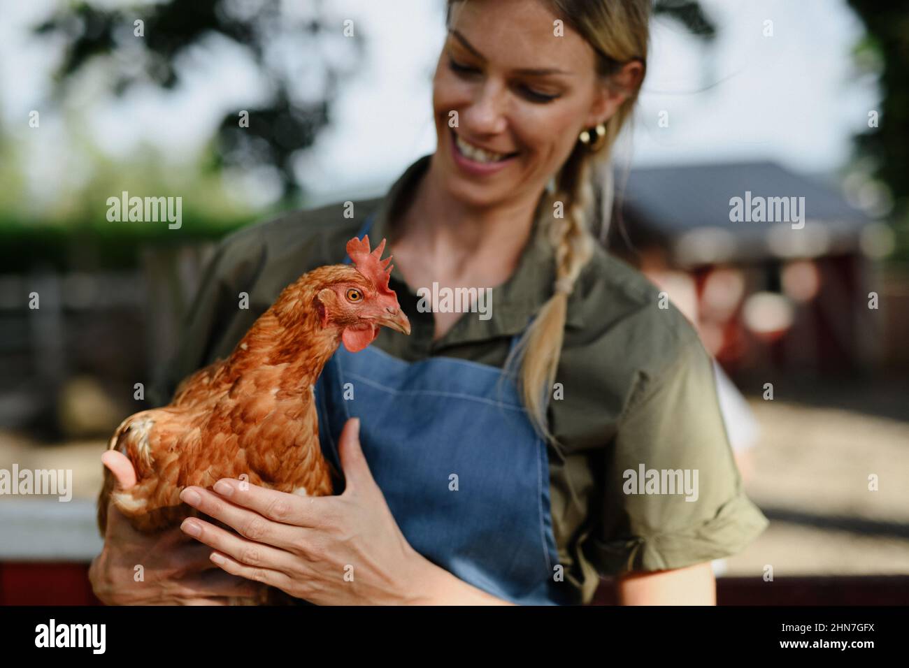 Cheerful farmer woman holding hen outdoors at farm Stock Photo - Alamy