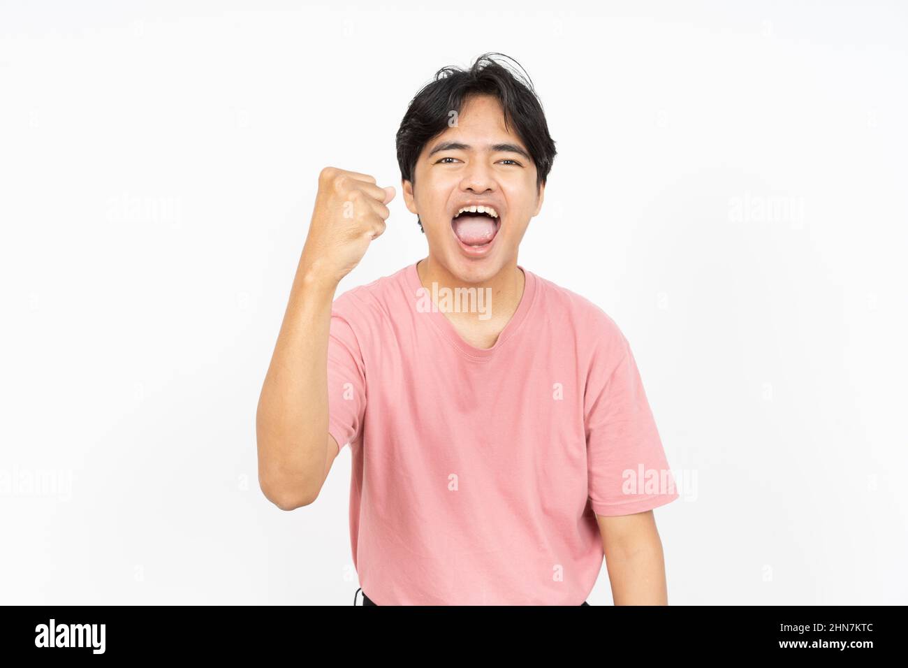 Victorious man. An asian man with t-shirt and white background Stock ...