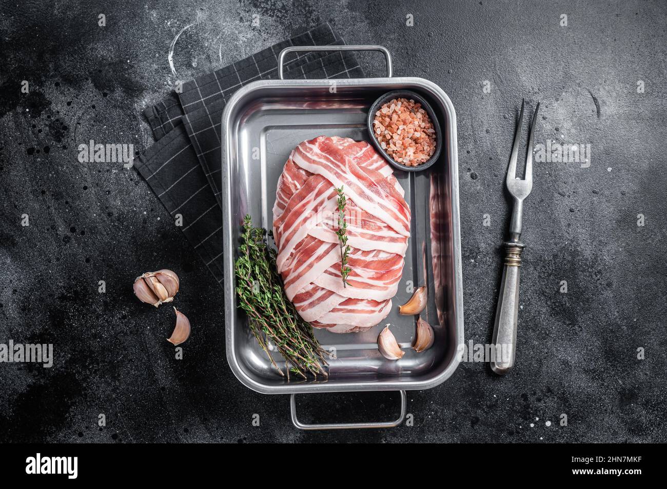 Cooking raw meatloaf with ground beef meat and bacon in steel tray ...