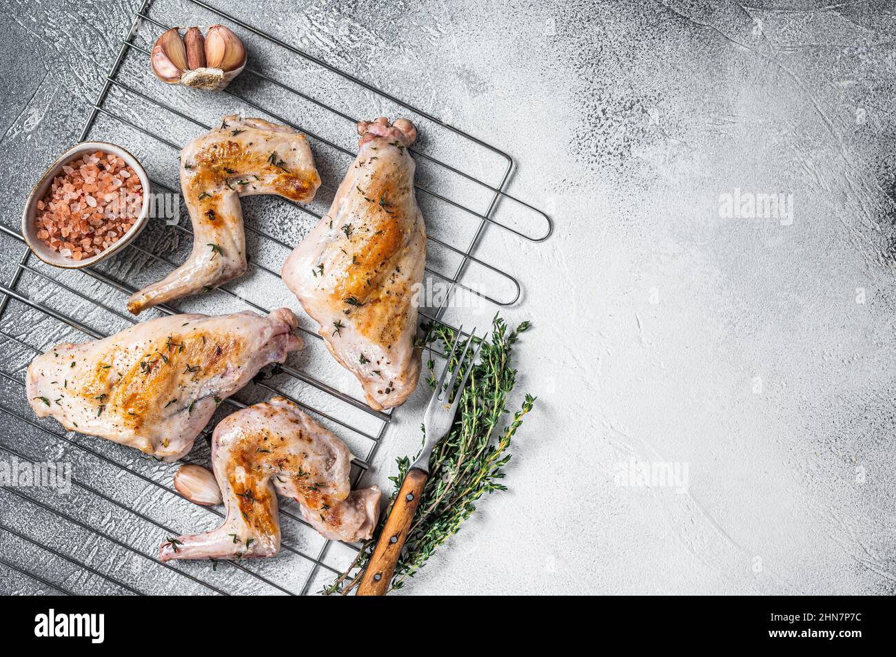 Baked rabbit legs on a grill with thyme. White background. Top view ...