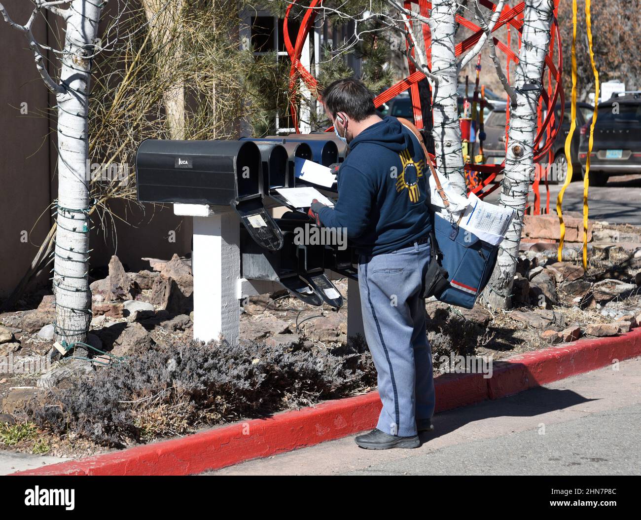 An American mailman or letter carrier delivers mail to a row of ...