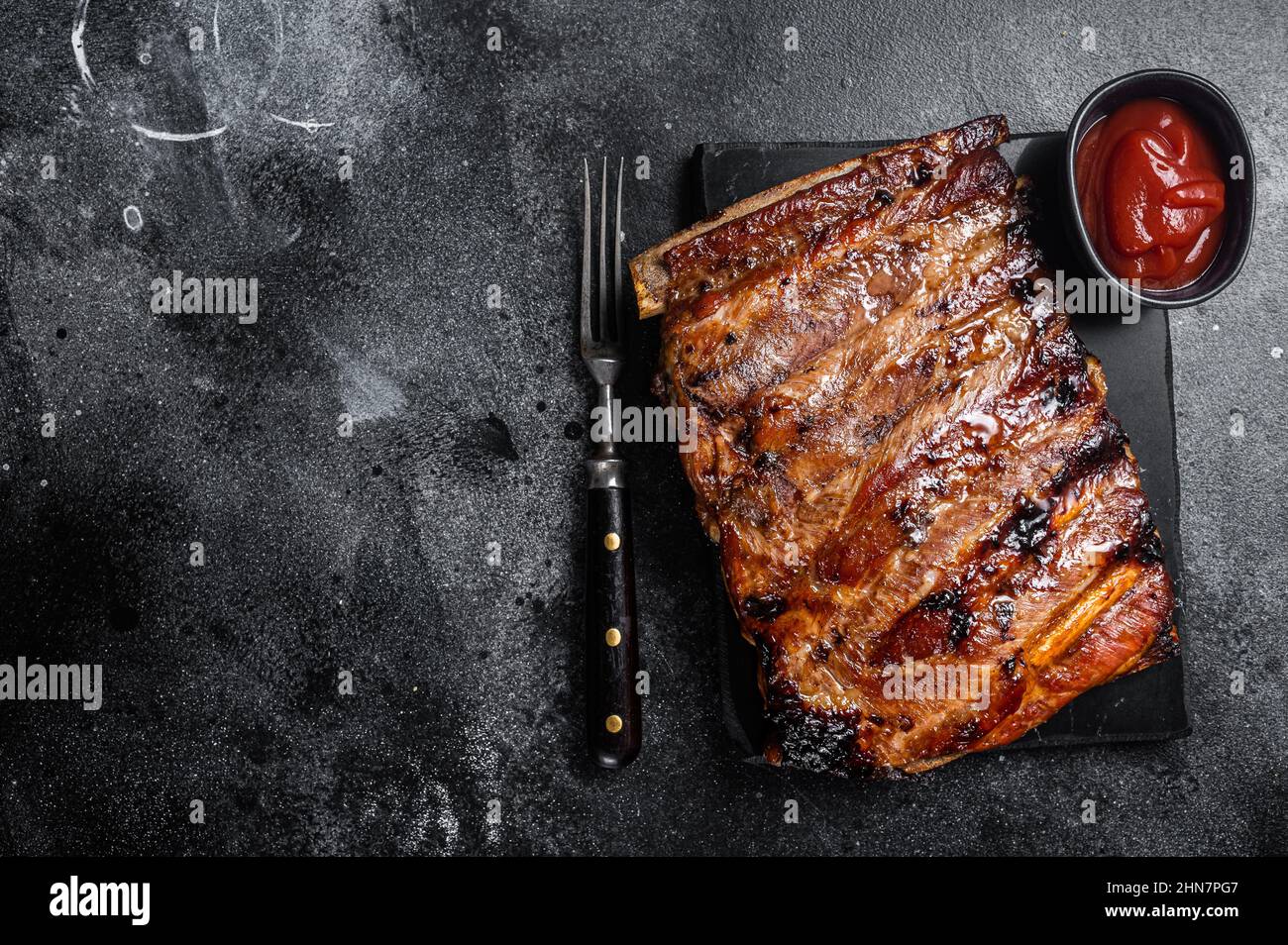 Full rack of BBQ grilled pork spare ribs on a marble board. Black ...