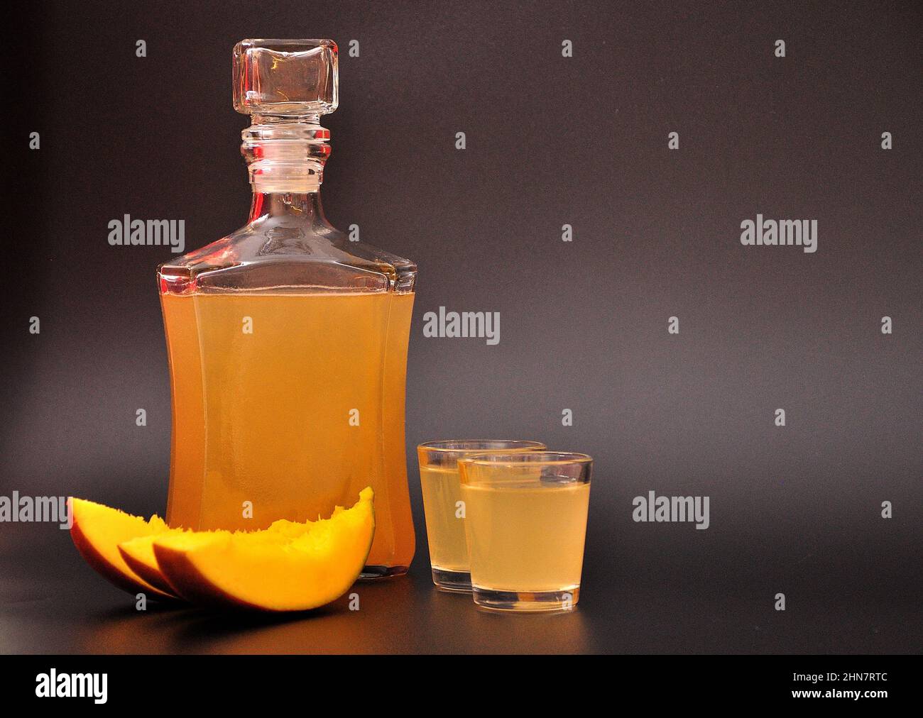 Mango liqueur, strong homemade alcohol in a bottle and glasses on a ...