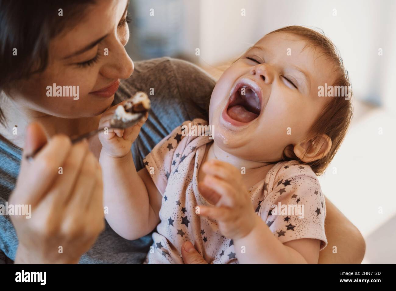 Caucasian mother feeding her baby girl. Baby refusing to eat food and ...