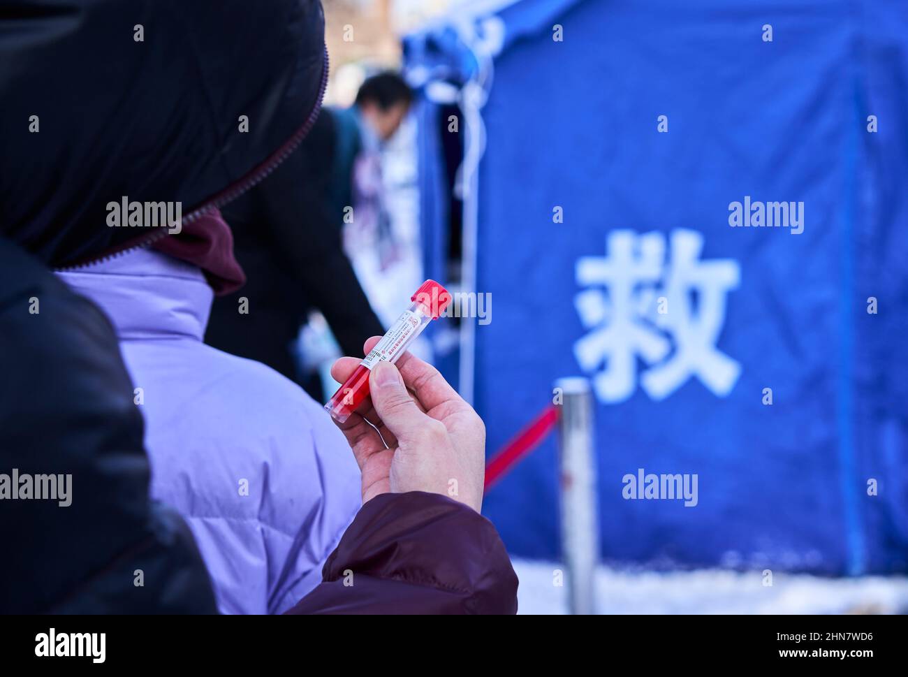 A person holds a sample collection tube in the queue ready to take the ...