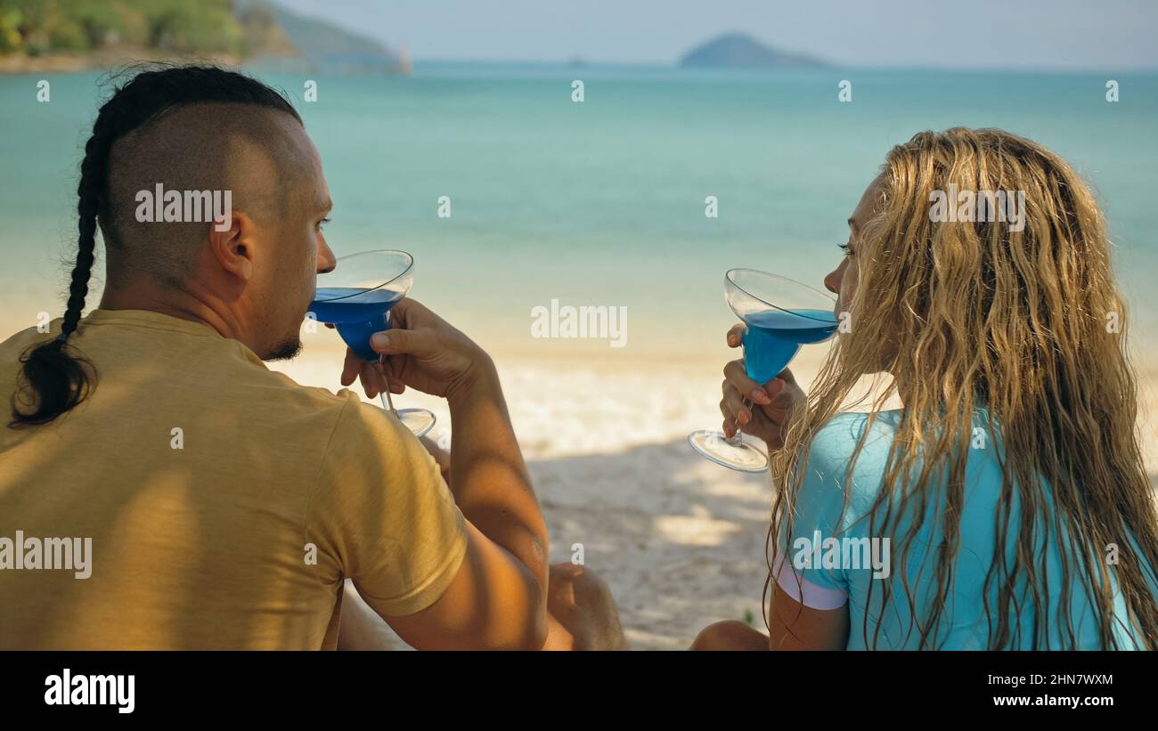 The love couple is holding a glass of blue curacao cocktail, on sea ...