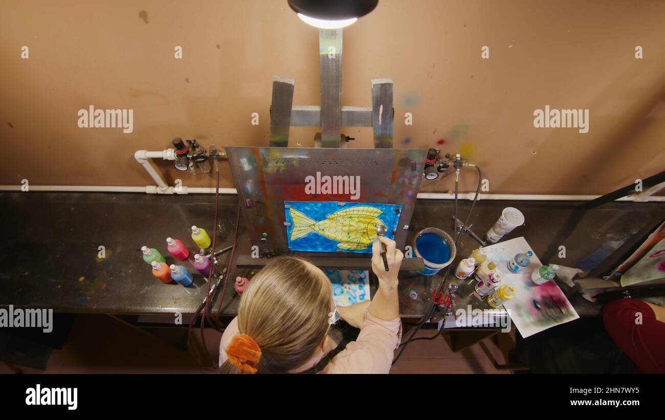 Woman artist learns to paint with airbrush with acrylic dye, paper and ...