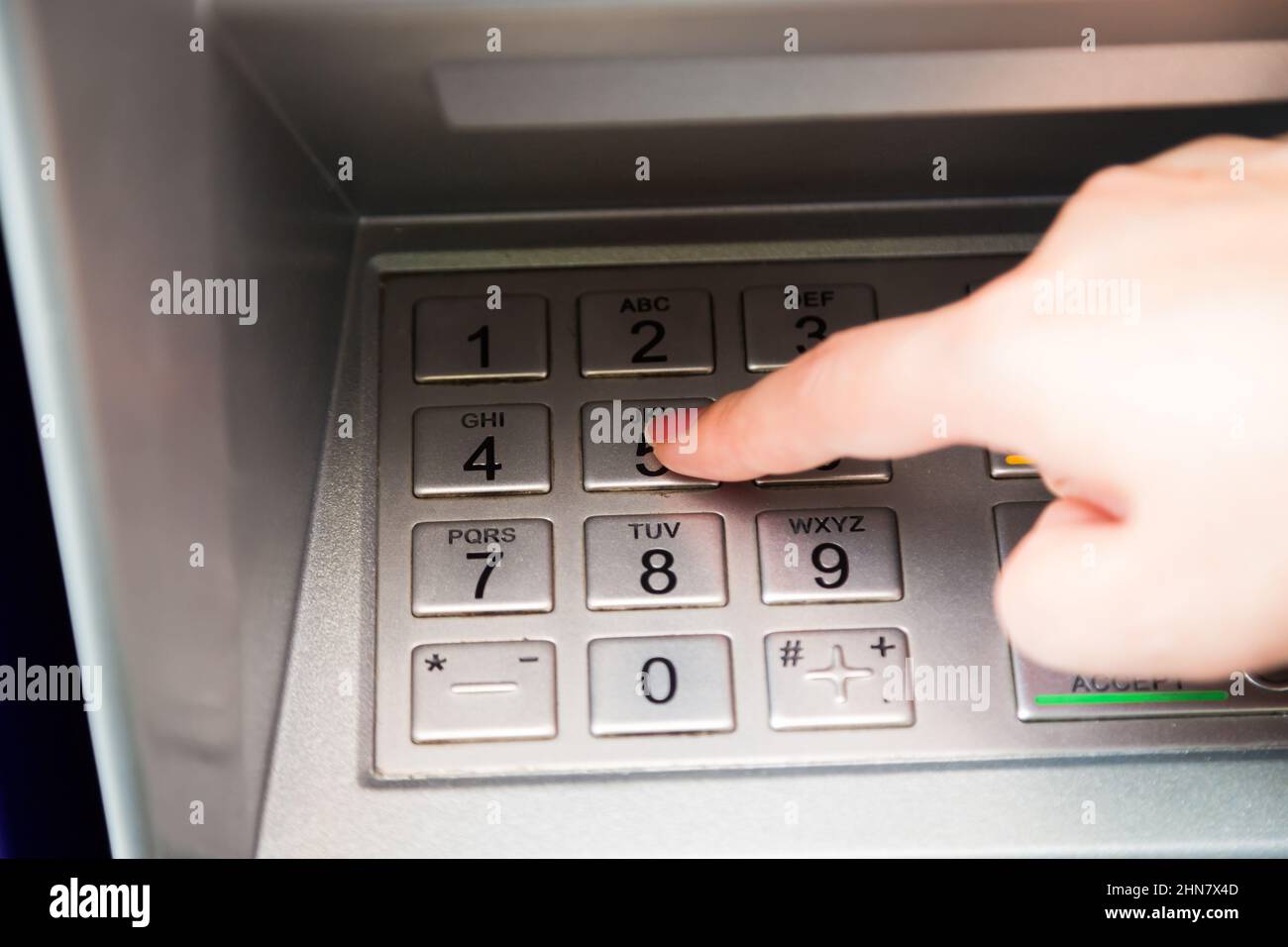 Close up of hand entering pin code at ATM machine to withdraw her money ...