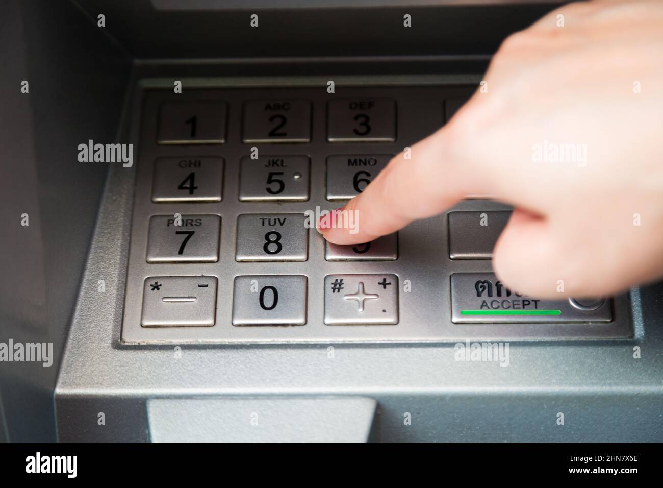 Close up of hand entering pin code at ATM machine to withdraw her money ...