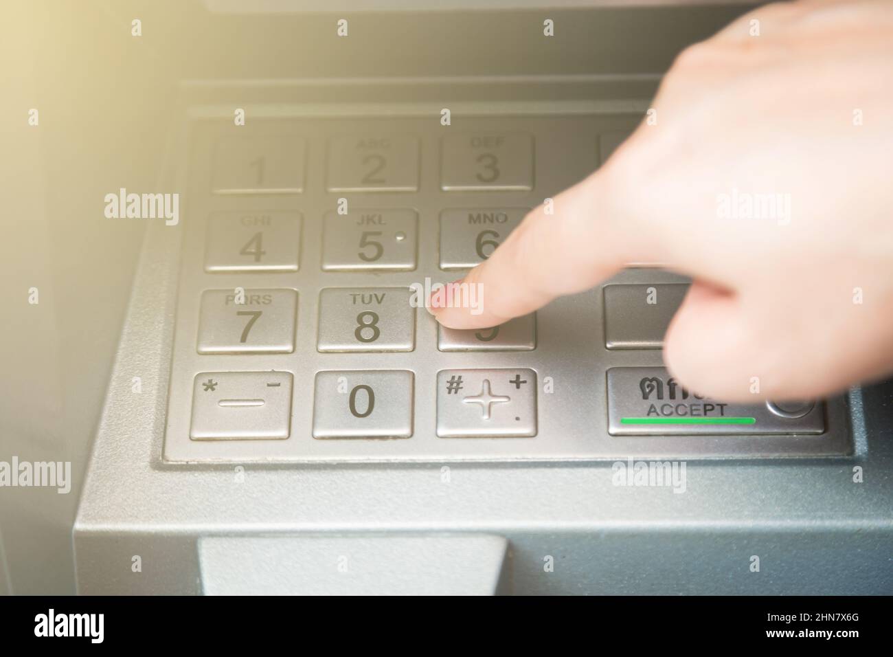Close up of hand entering pin code at ATM machine to withdraw her money ...