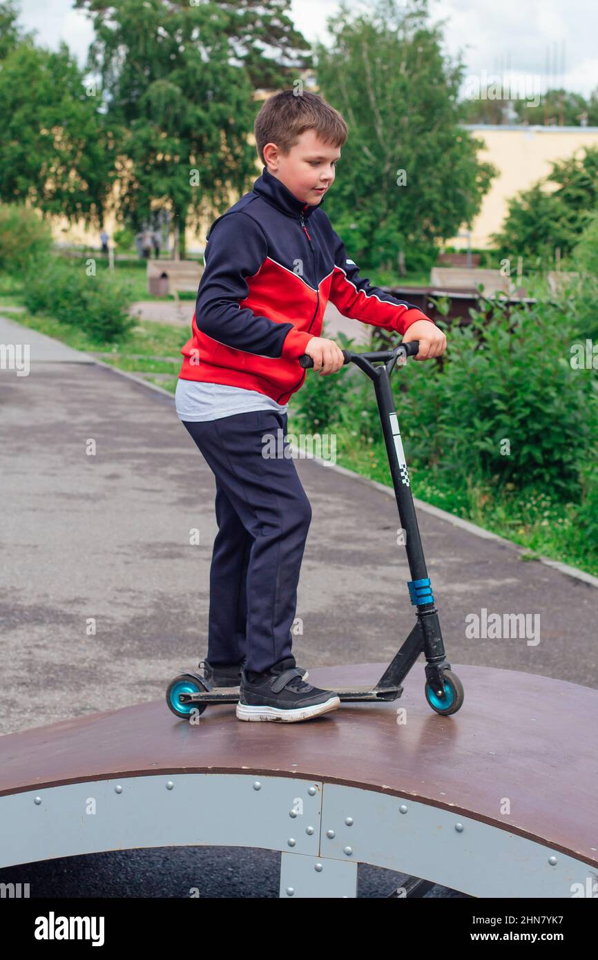 Cute boy riding scooter in a summer park. Happy teenager riding a ...