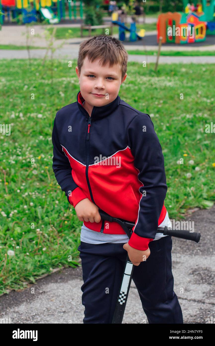 Cute boy riding scooter in a summer park. Happy teenager riding a ...