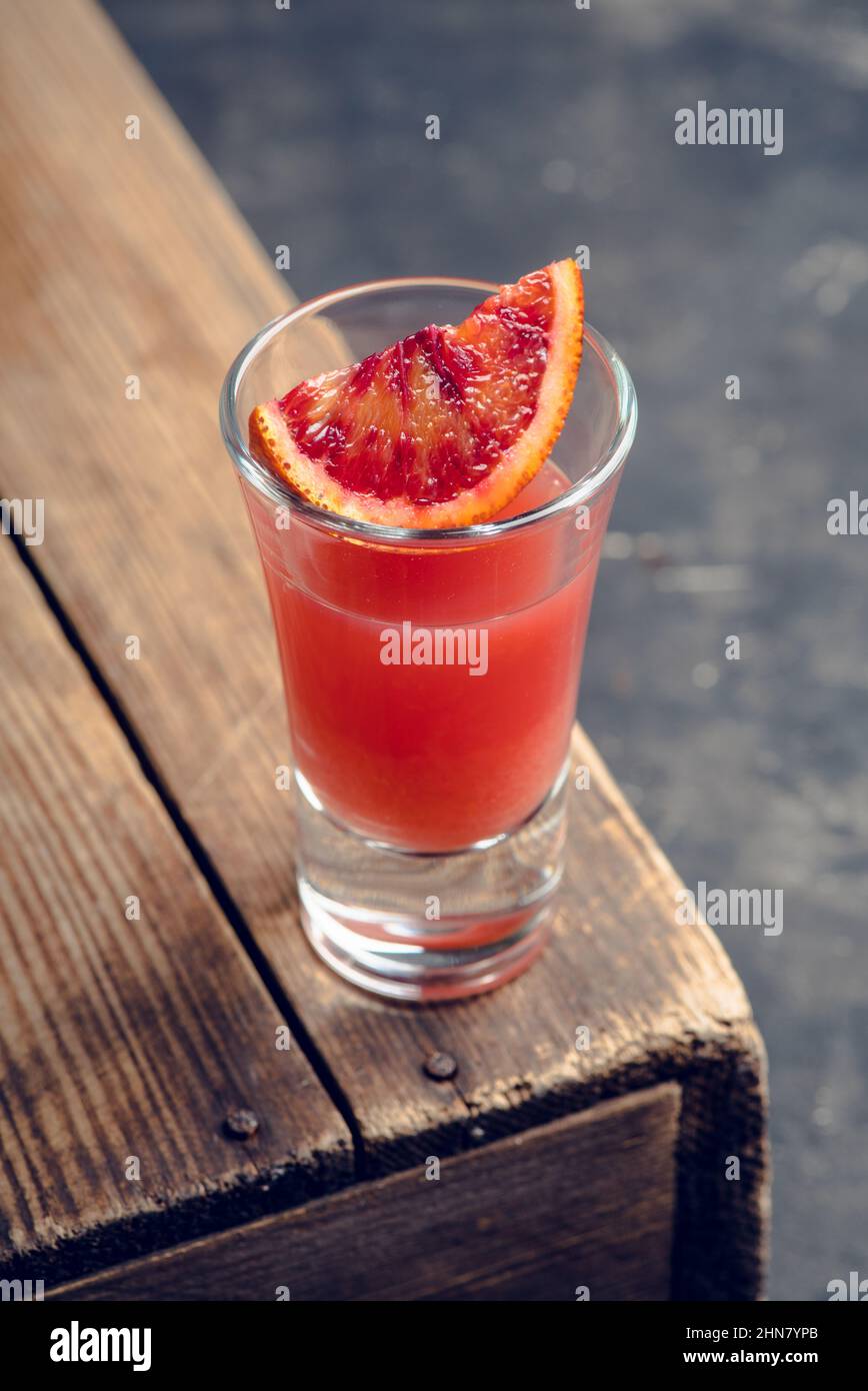 Strong red cocktail in shots on the rustic background. Selective focus ...