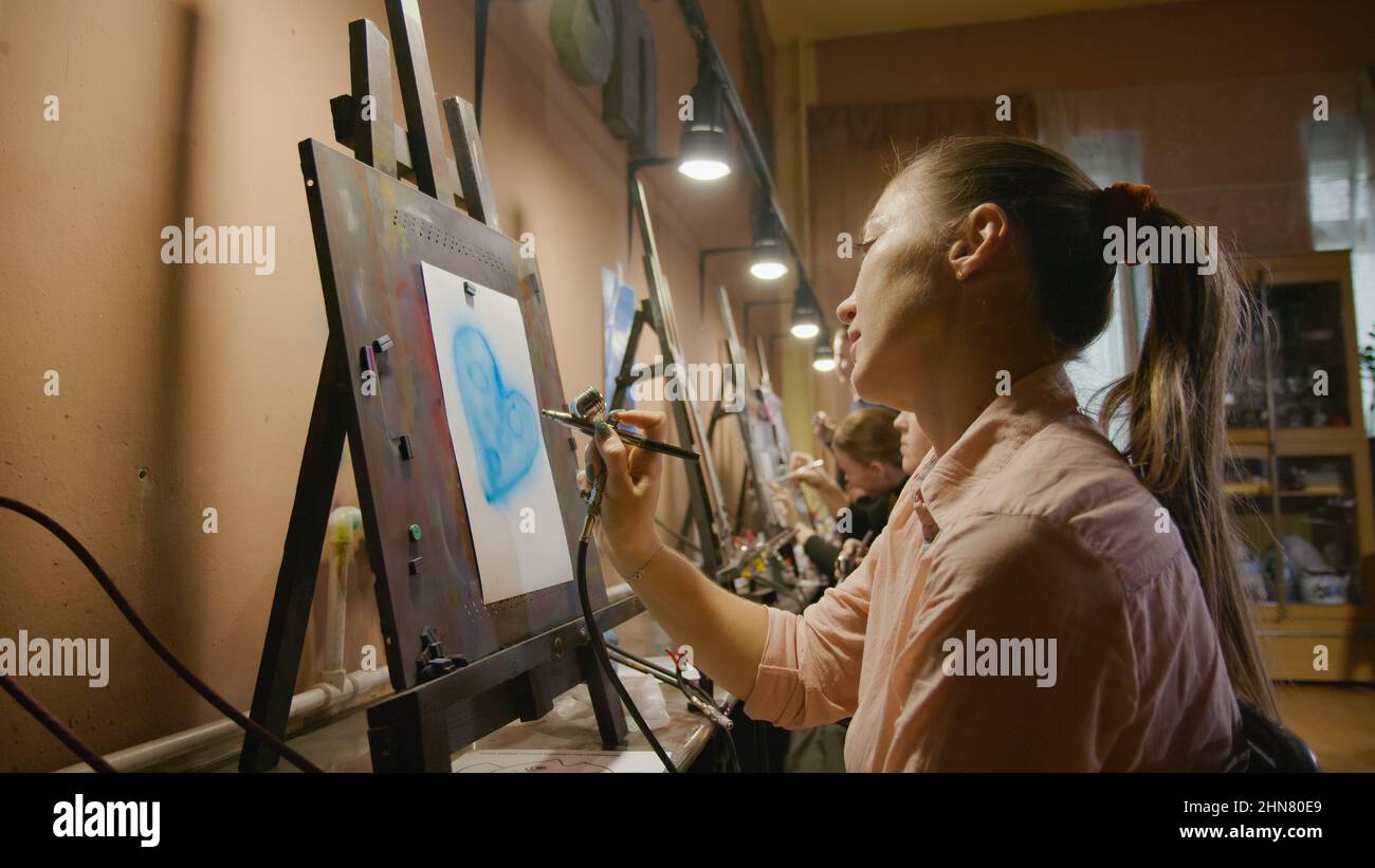 Woman artist learns to paint with airbrush with acrylic dye, paper and ...