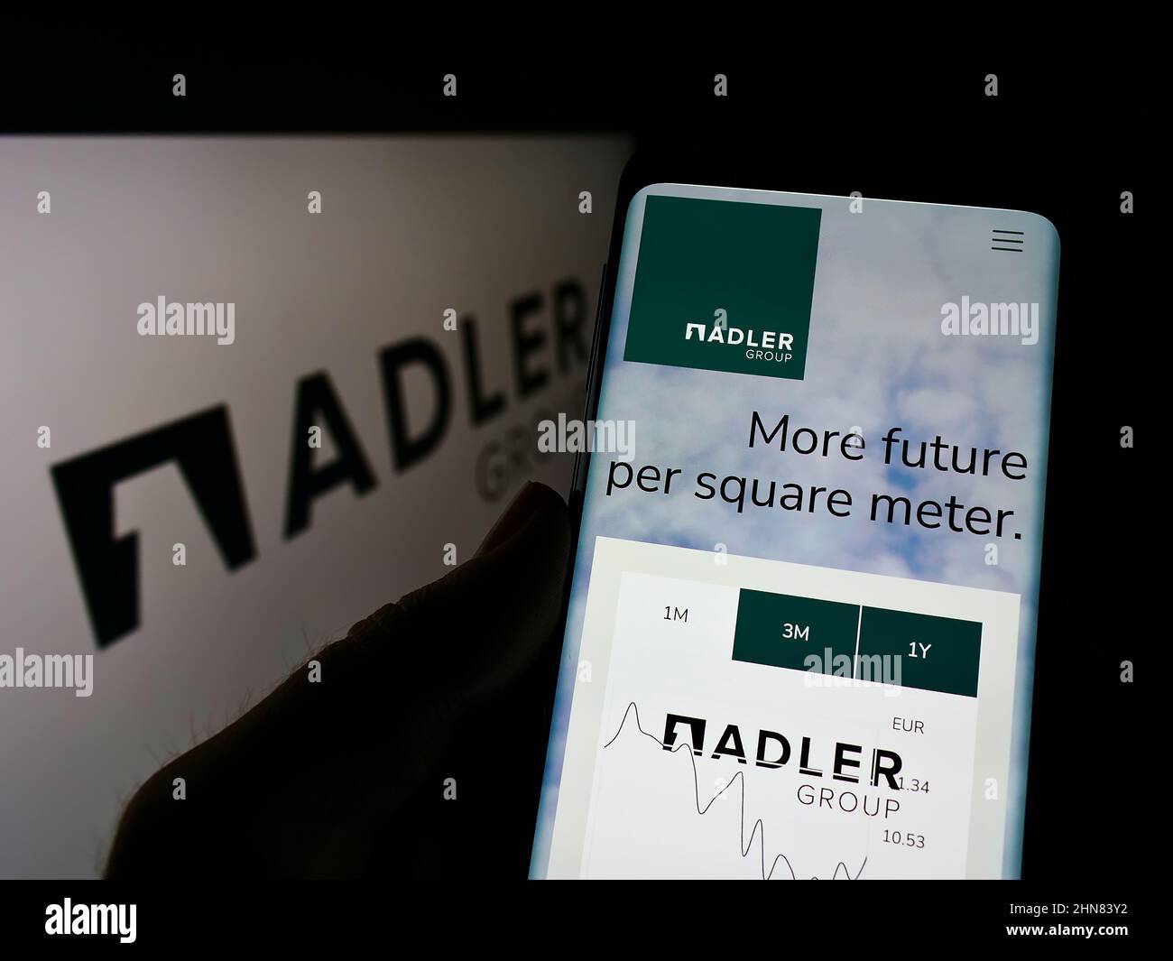 Person holding mobile phone with webpage of real estate company Adler ...